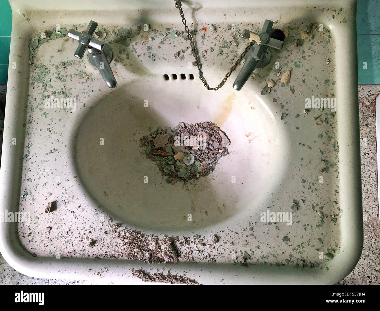 Sink in abandoned house, with paint chips and plaster debris that have ...