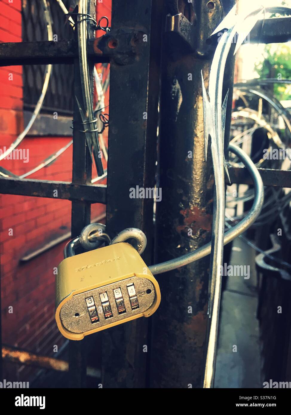 Combination lock on a street side gate with razor wire, NYC, USA Stock ...