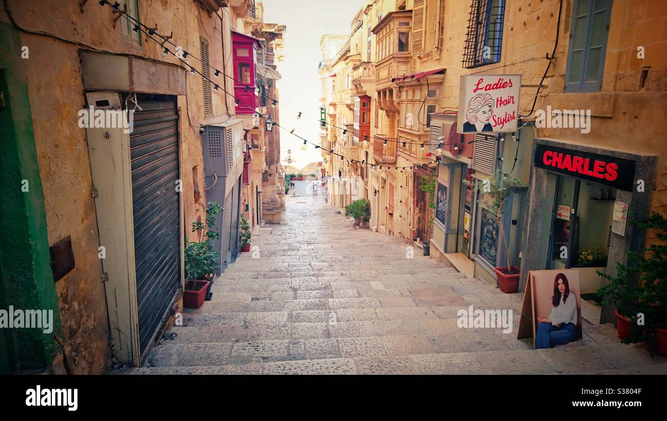 A photograph of a street in Valletta, Malta. Typical stone steep urban ...
