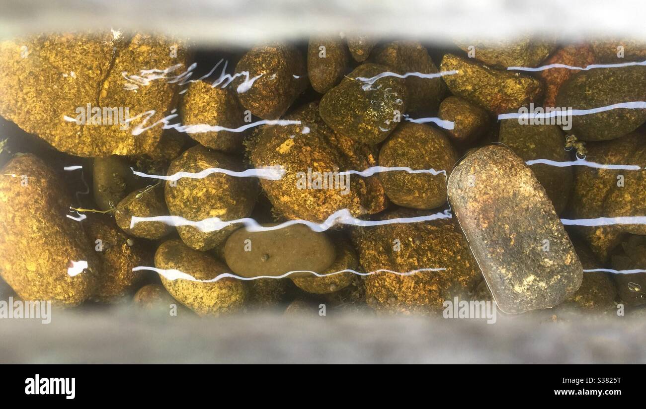 Water gently streaking across submerged rocks. Concepts: hard, soft ...