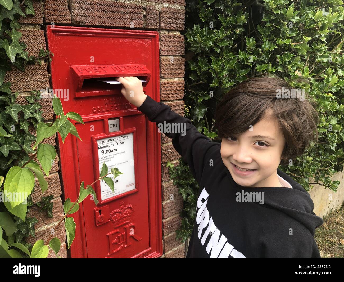 Young boy posting a letter in a postbox Stock Photo - Alamy