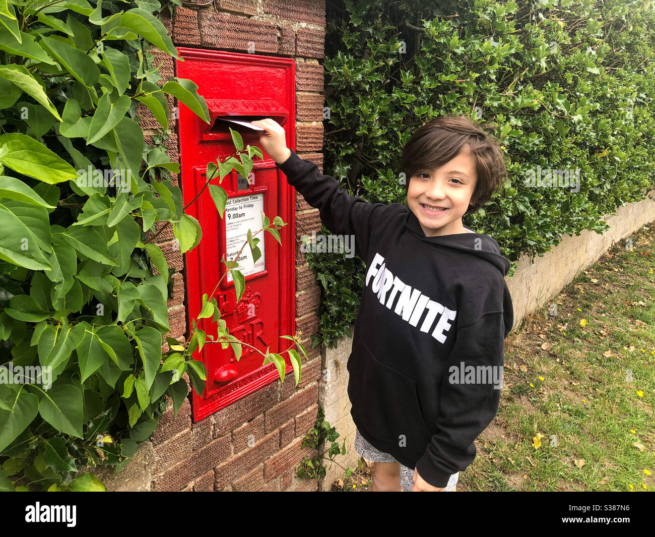 Young boy posting a letter in a postbox Stock Photo - Alamy