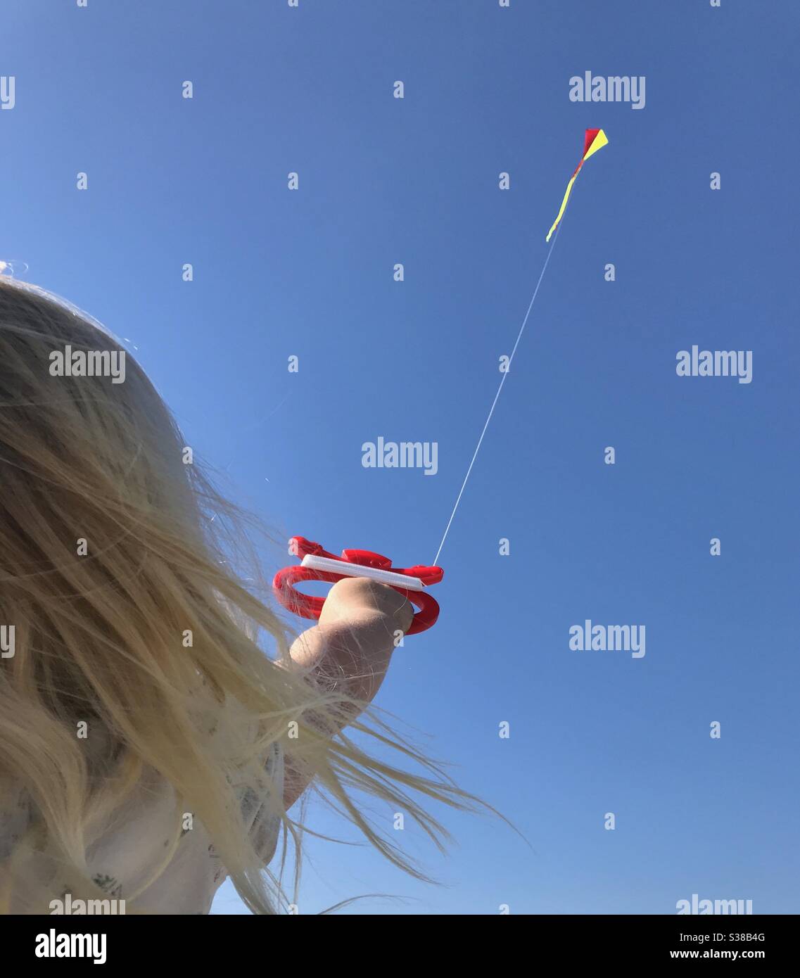 Young blonde girl flying a kite Stock Photo - Alamy