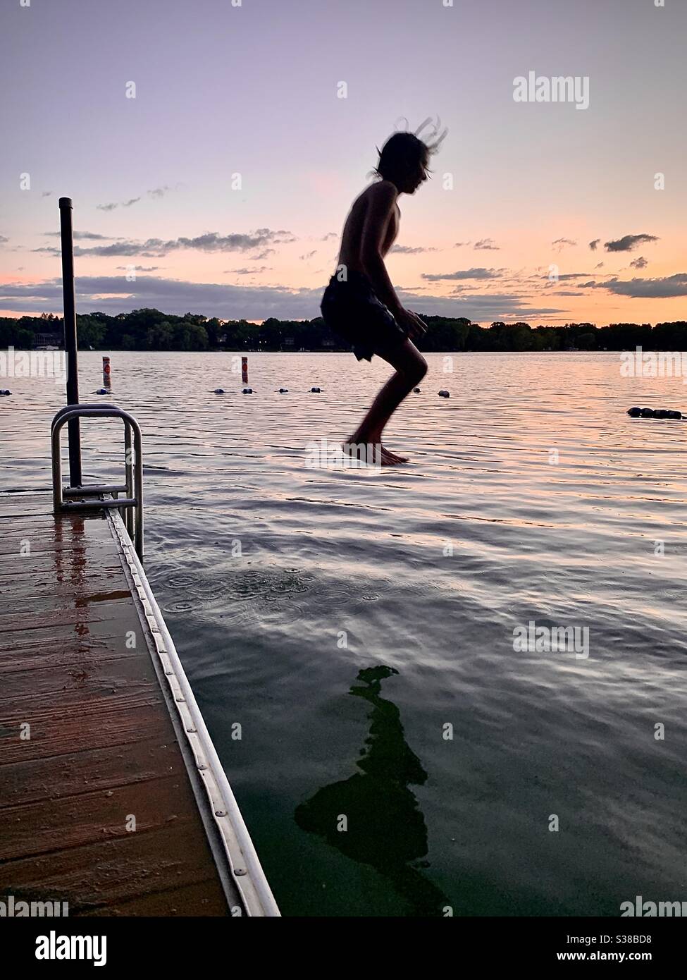 Teen boy jumping off of a dock Stock Photo - Alamy