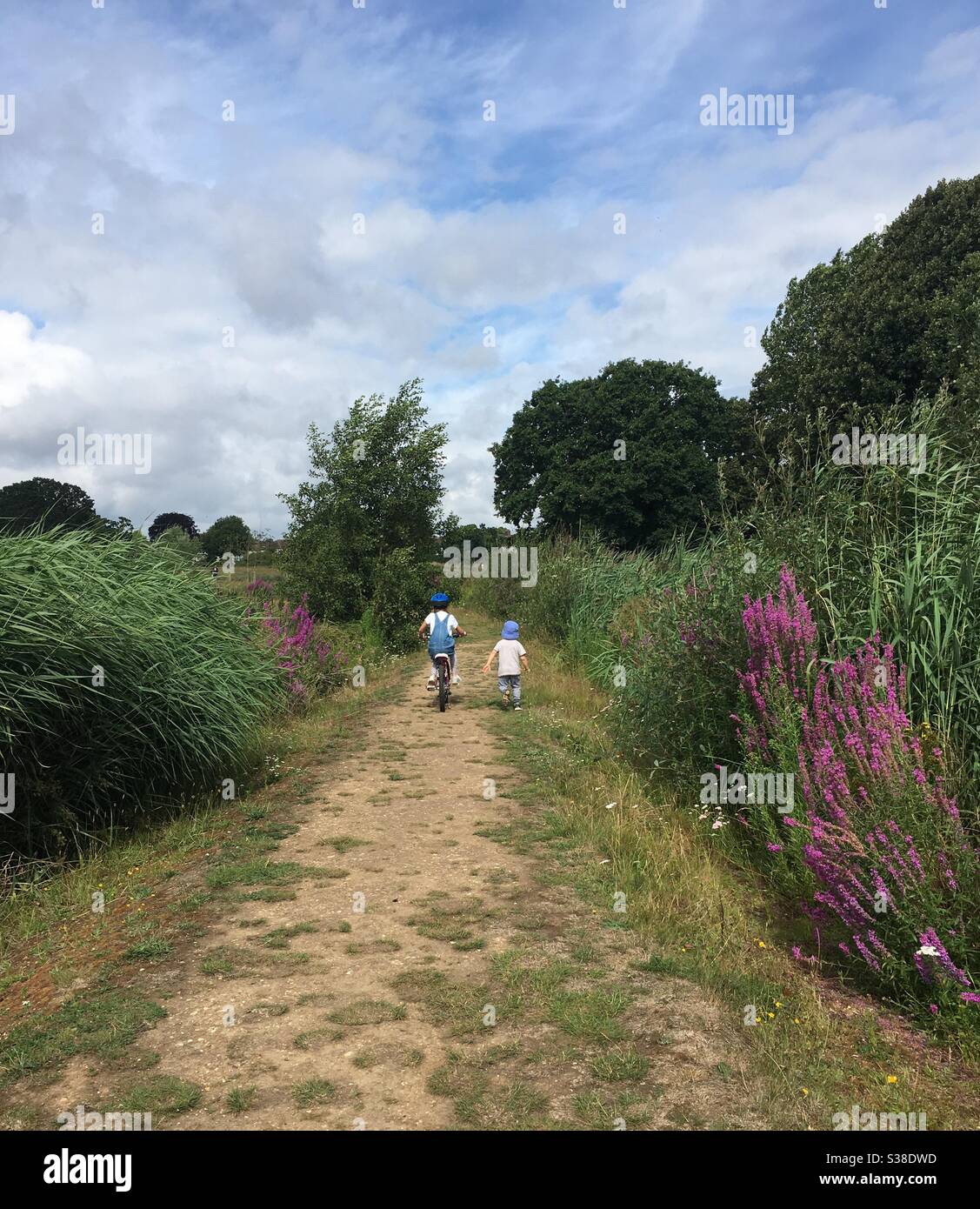 Children riding a bike and running along pathway in the countryside ...
