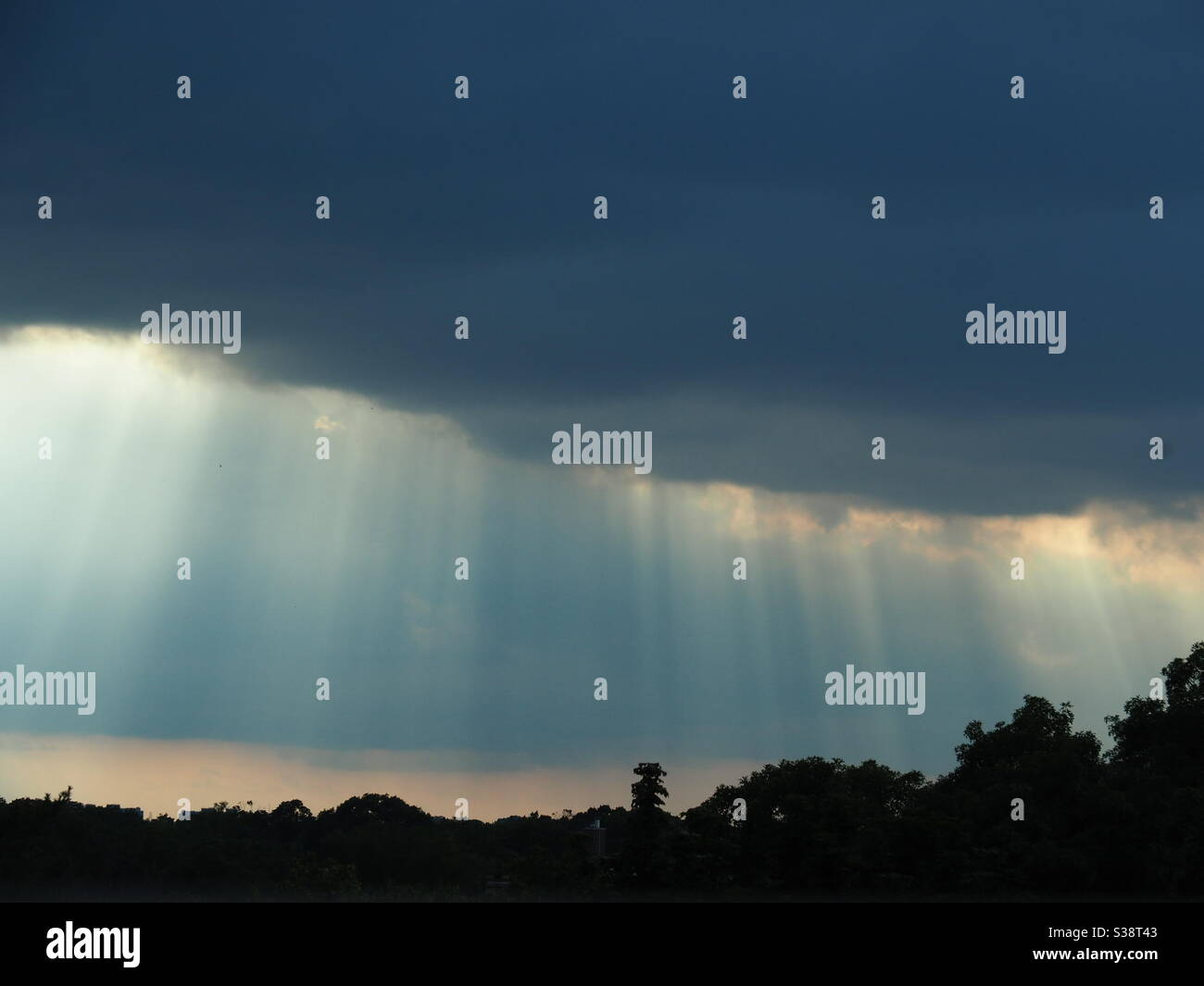 Sun rays shine through dark clouds Stock Photo - Alamy