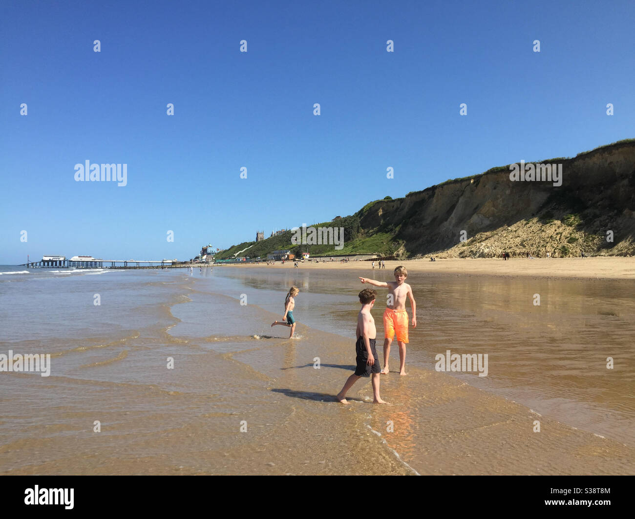 Kids playing on a UK beach. Blue sky. No editing on photo. No eye ...