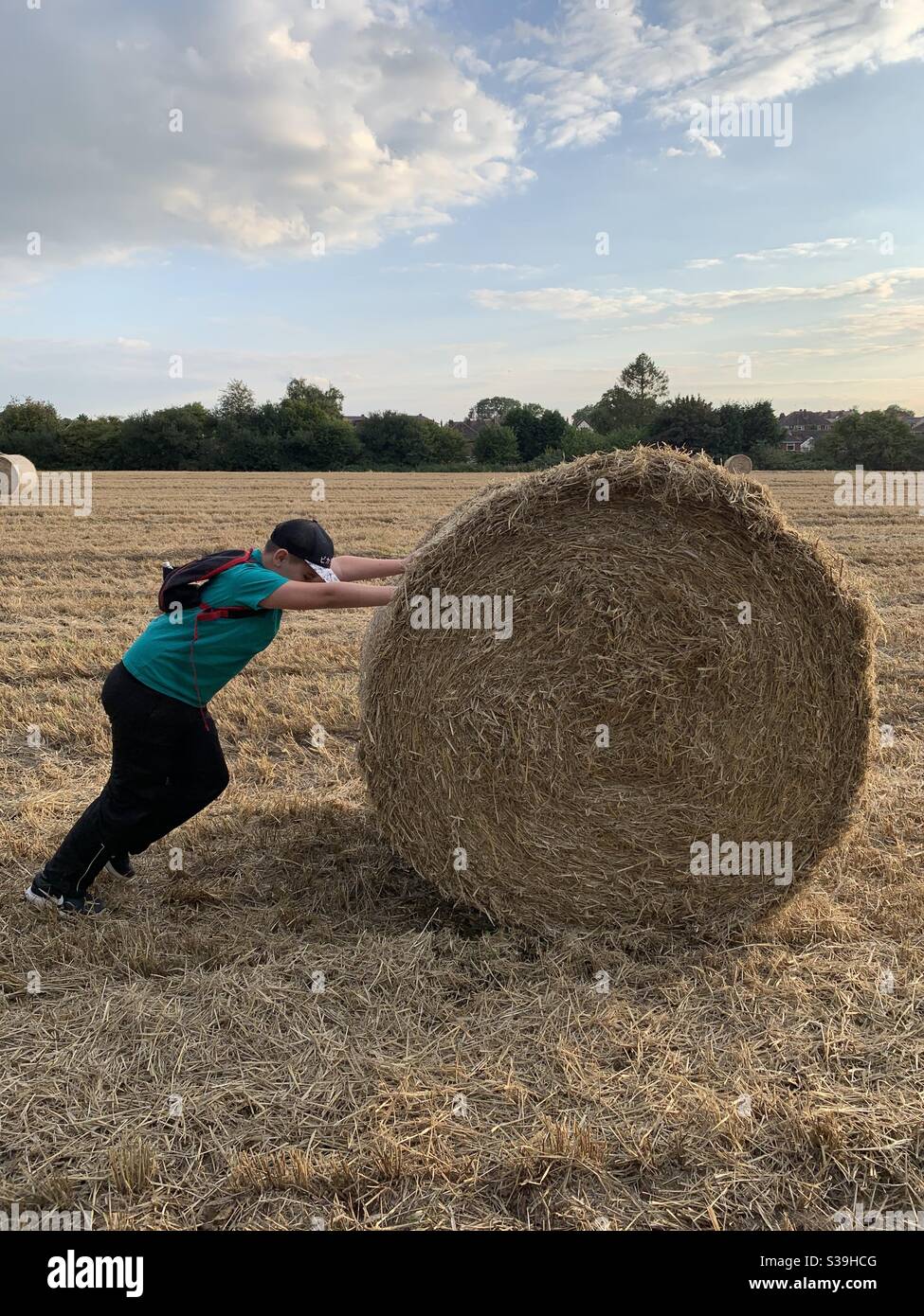 Boy pushing hay bale Stock Photo - Alamy