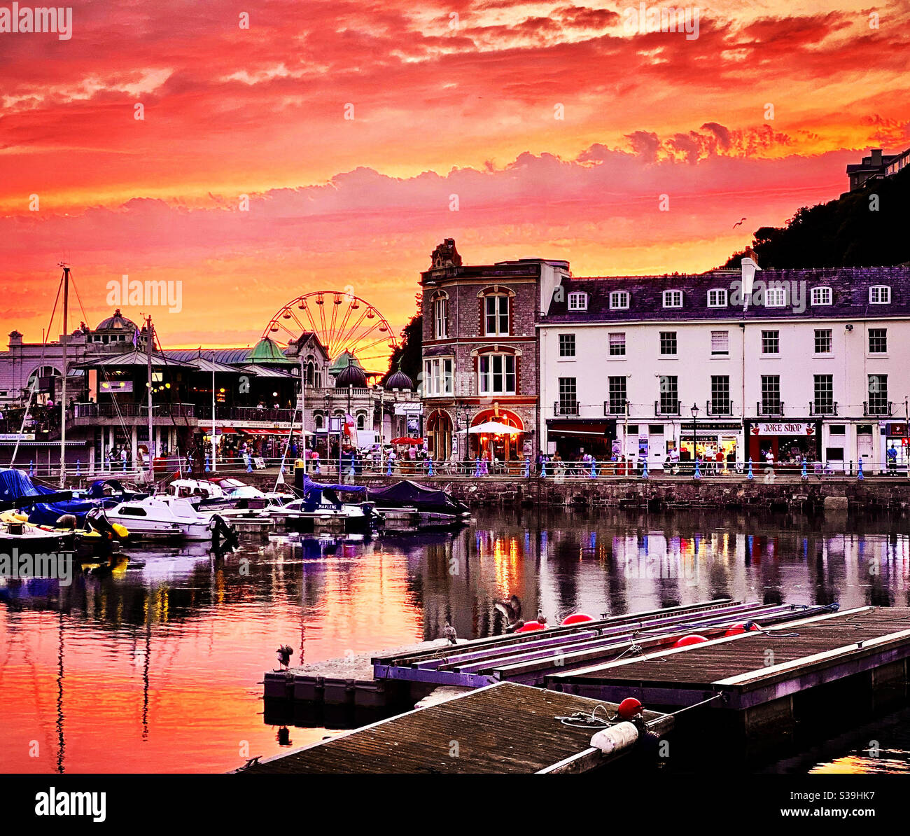 A colourful red sky lights up the harbour side during sunset at Torquay ...