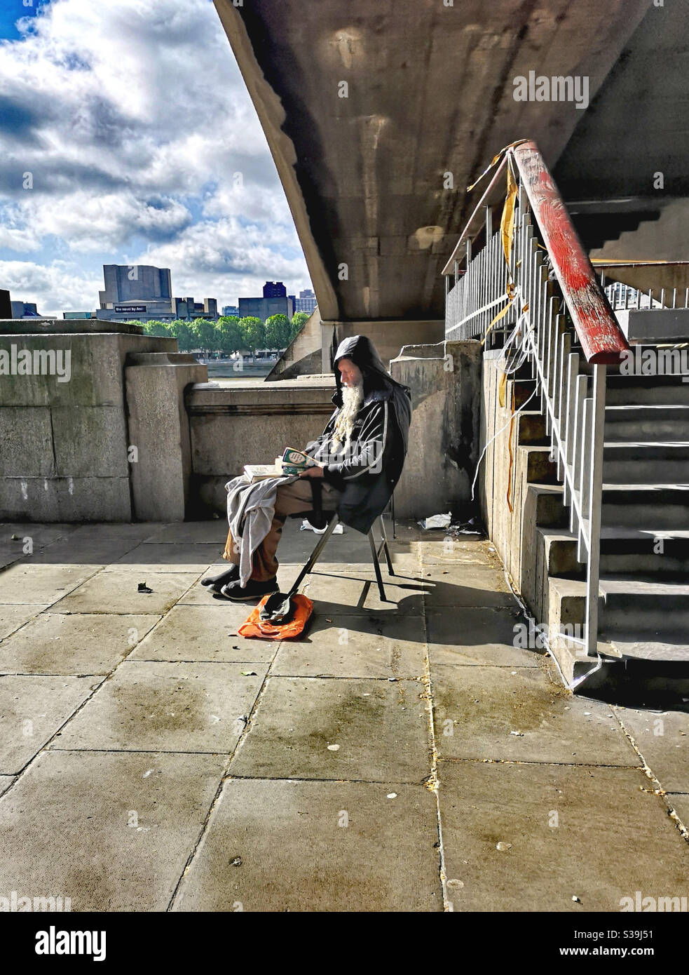 Homeless man reading in the sun under a bridge in London Stock Photo ...