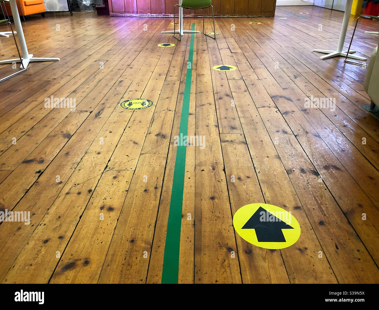 Markings on a wooden hall floor mark out a one way system as a ...