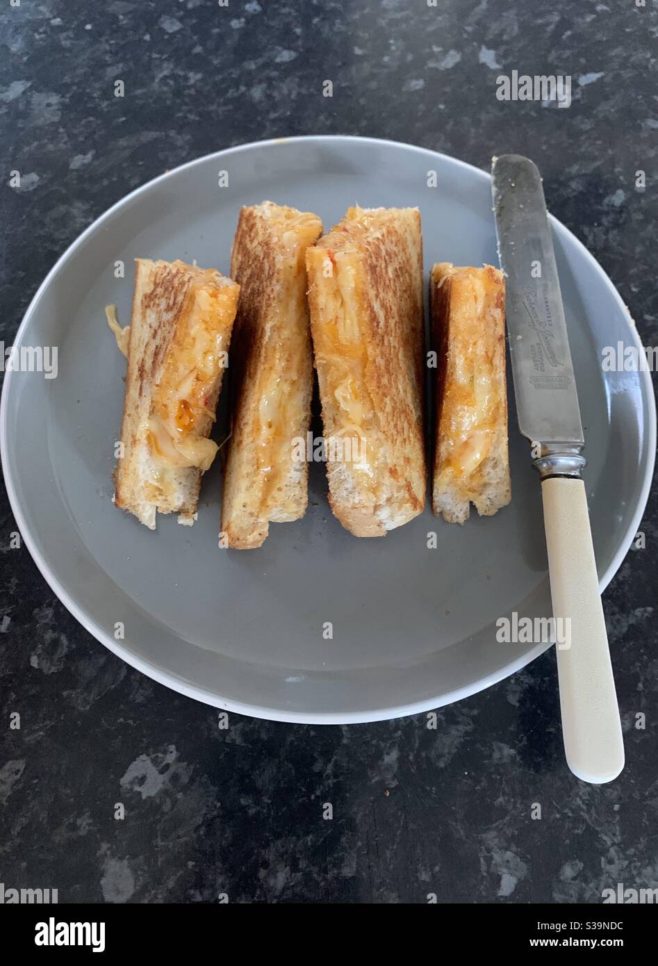 Cheese toastie with a butter knife on a small grey plate Stock Photo ...