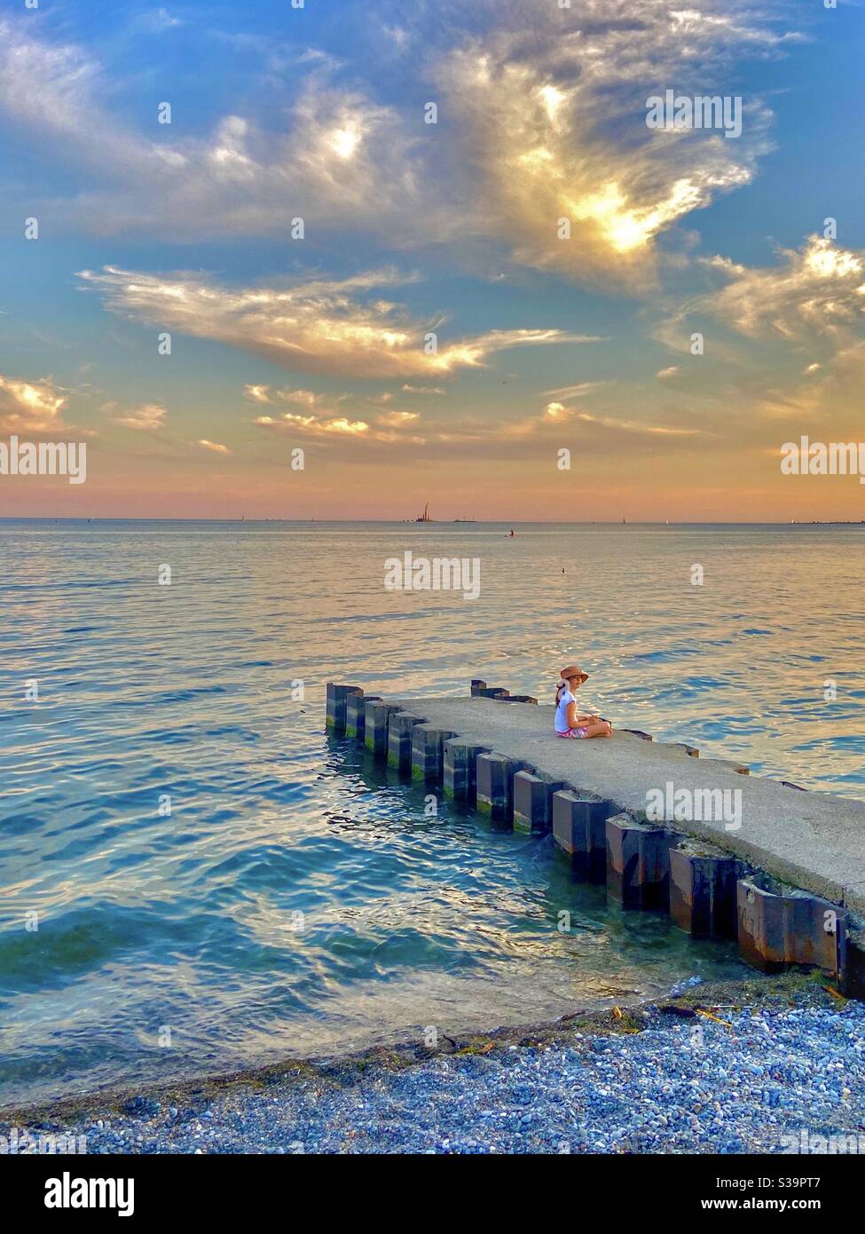 A colorful sunset walk by the beach. A girl sits at a pier. Toronto ...