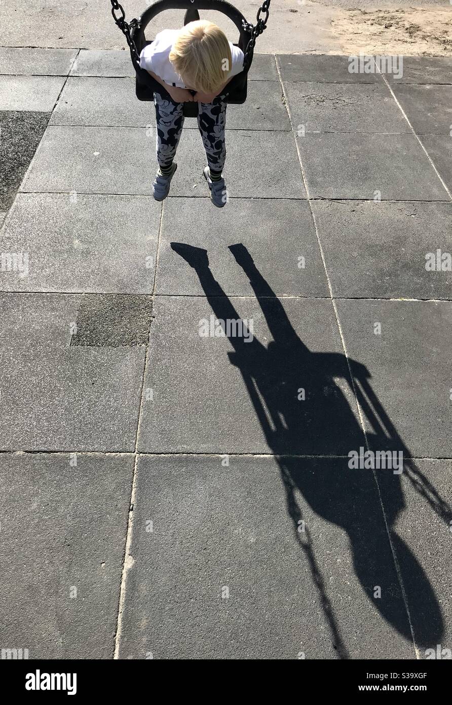 A child looks at his shadow while on a swing Stock Photo - Alamy