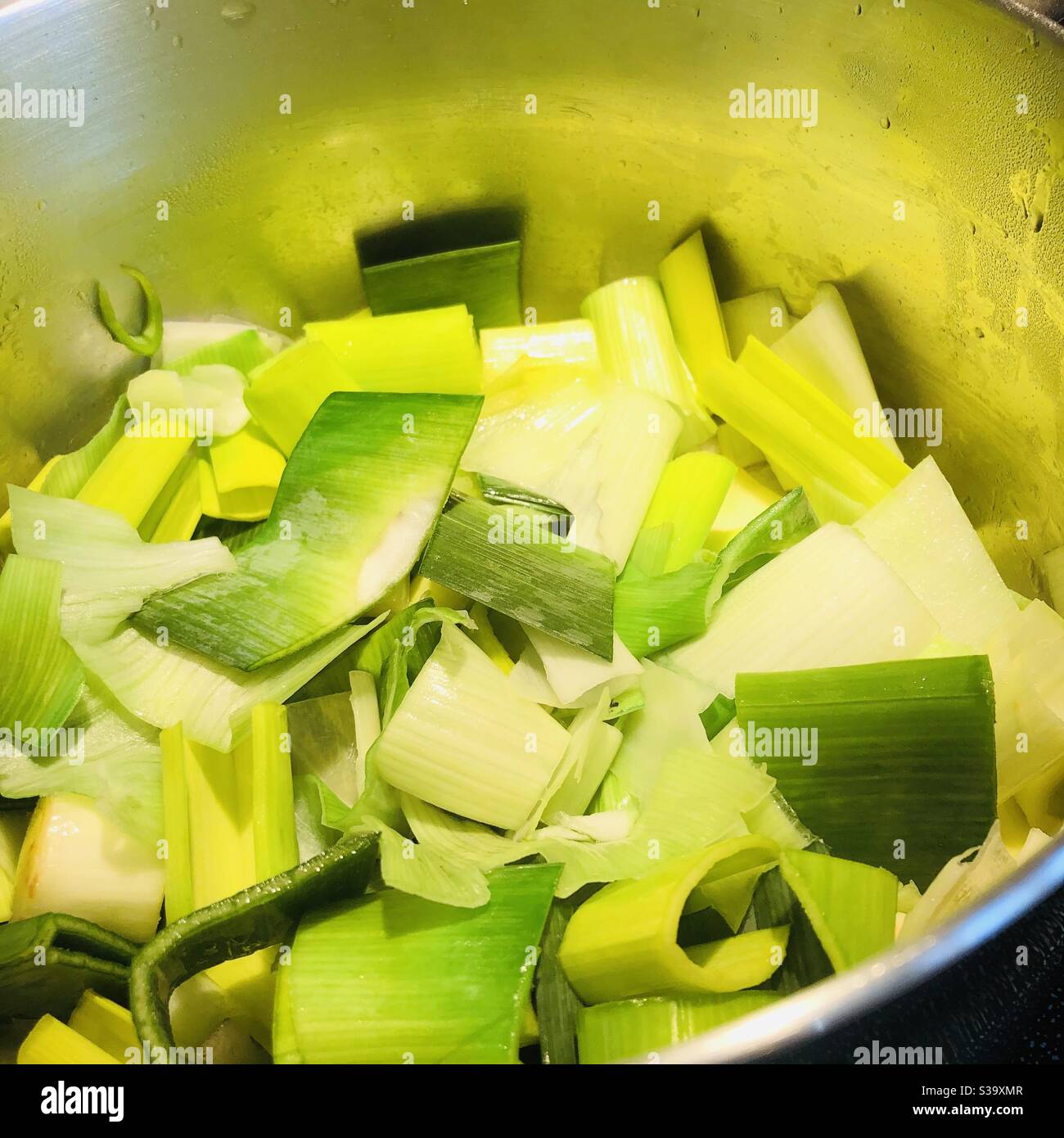 Preparation of a soup. Pieces of green leak in a stainless steel pot ...