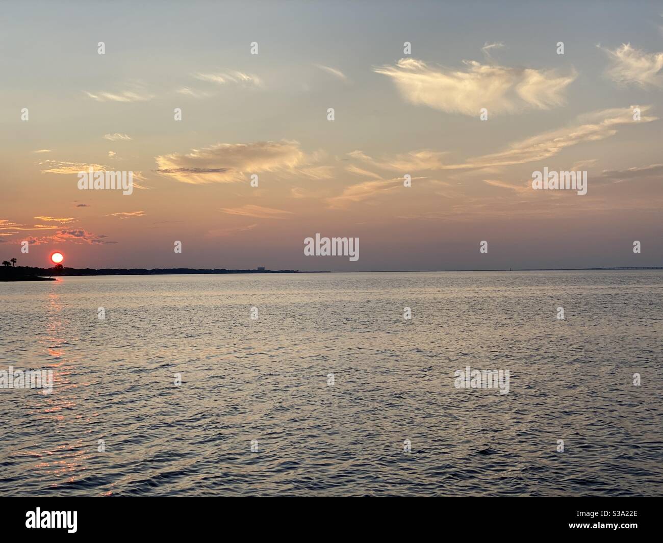 Sun setting over bay water with colorful skies Stock Photo - Alamy
