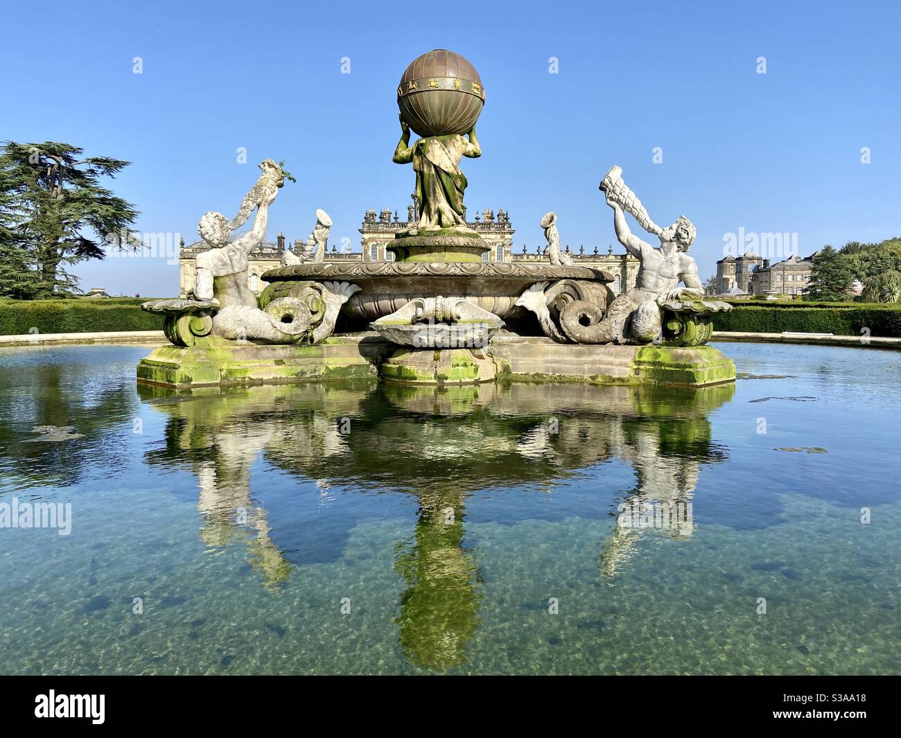 Atlas Fountain at Castle Howard with blue sky and still water ...