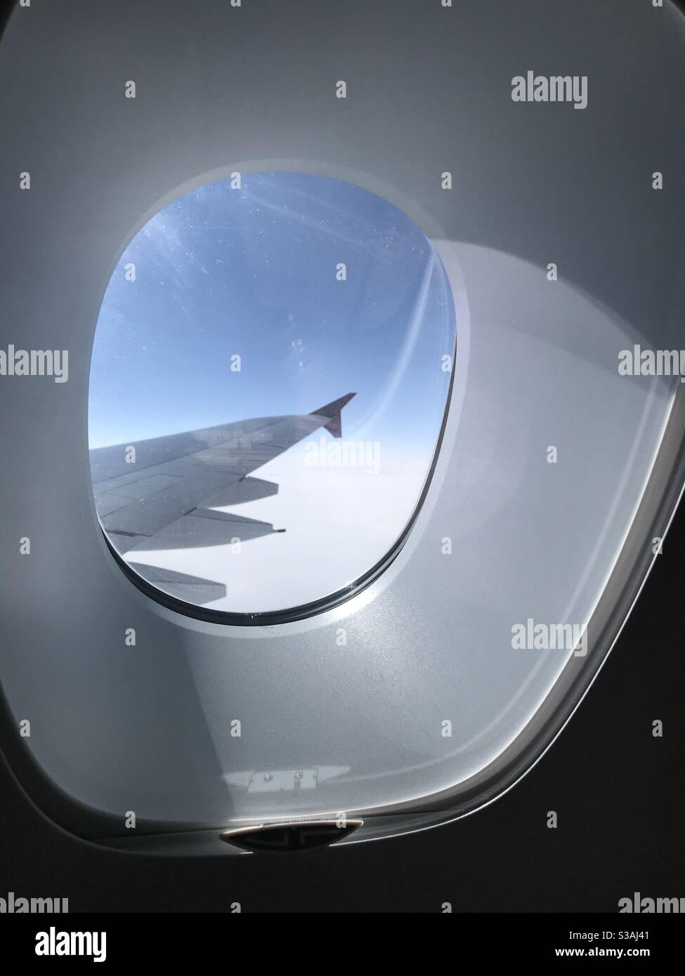 View of the wing of an aircraft taken from a plane window mid flight ...