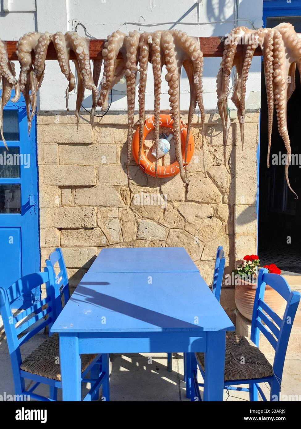 Traditional Greek taverna with octopus drying under the sun, set ...