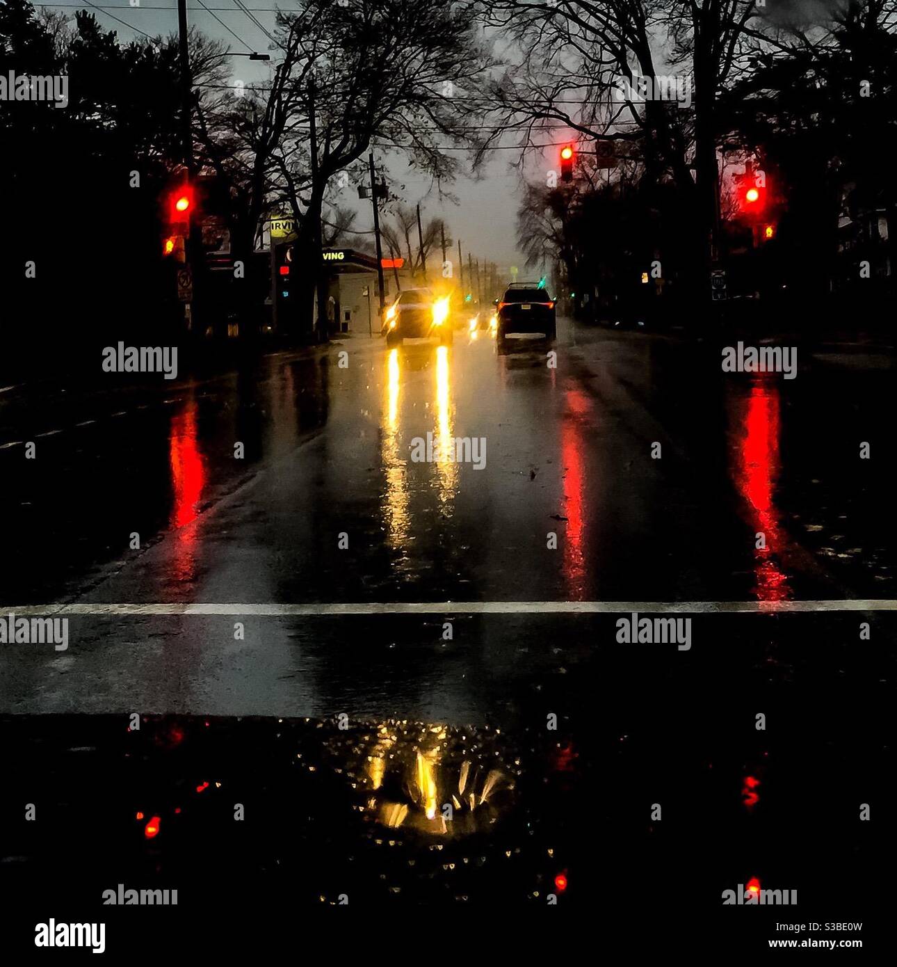 Vehicle approaching Red Lights at intersection in the rain Stock Photo ...