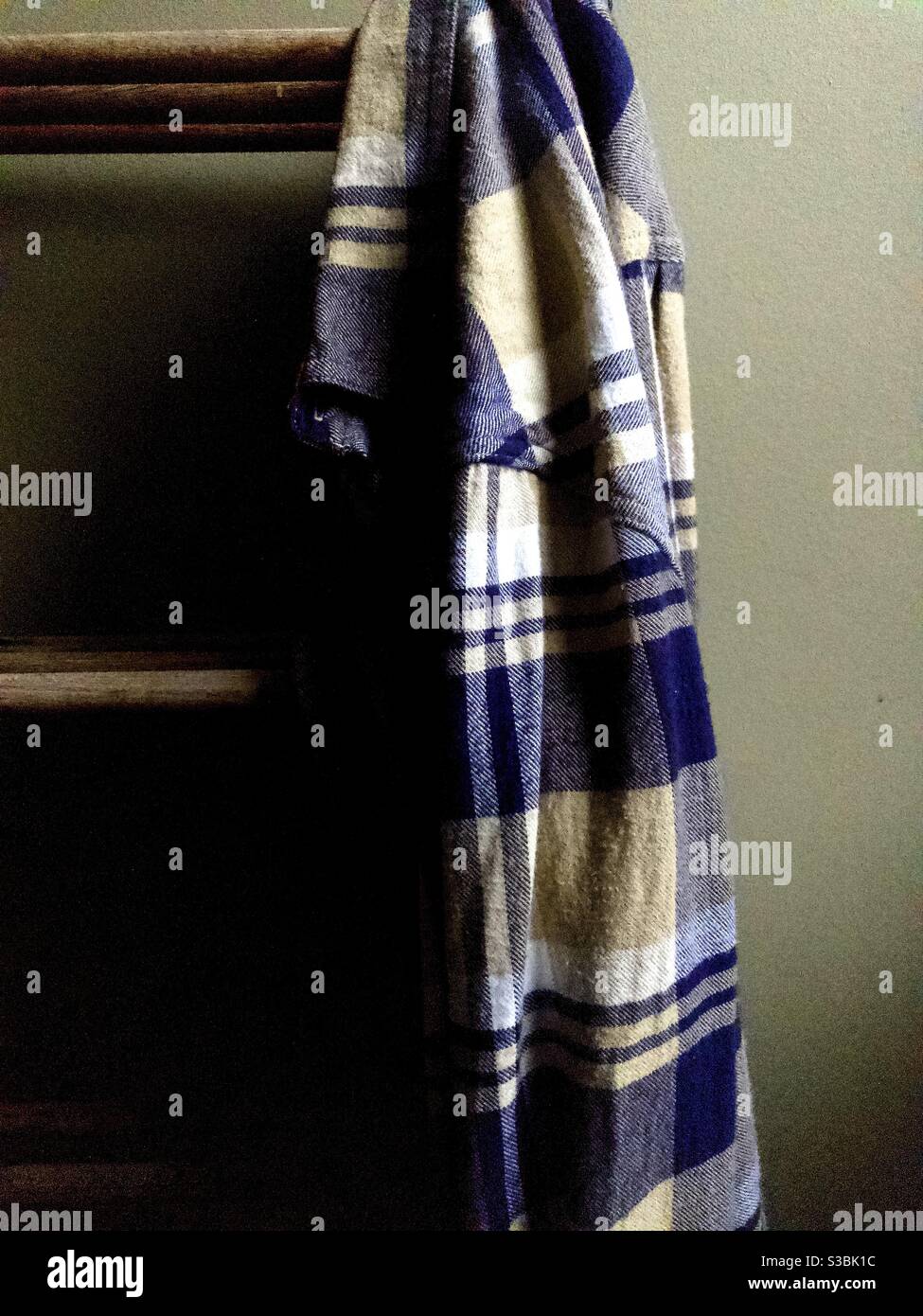 Blue plaid flannel shirt on wooden clothes rack by window Stock Photo ...