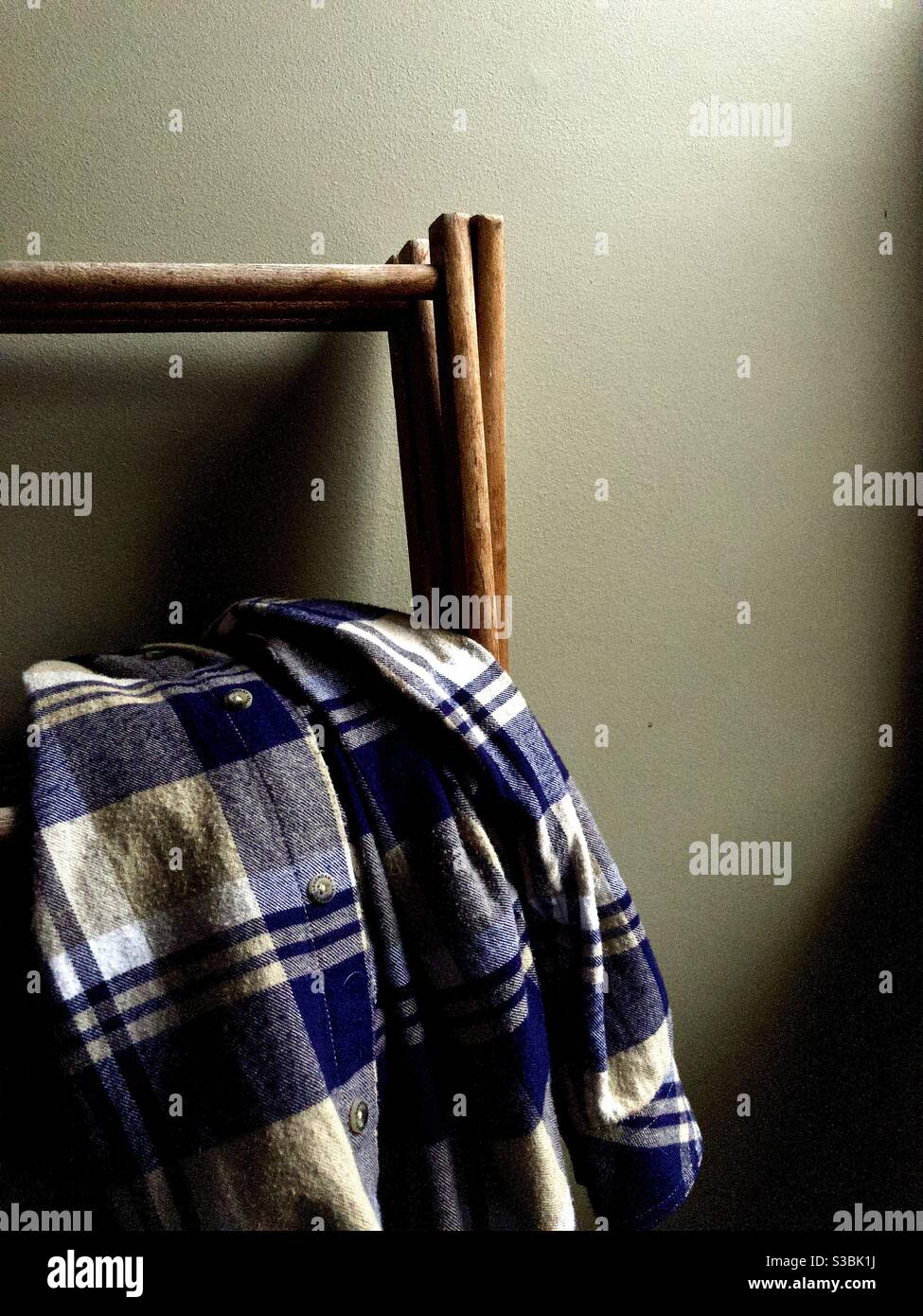 Blue plaid flannel shirt on wooden clothes rack by window Stock Photo ...