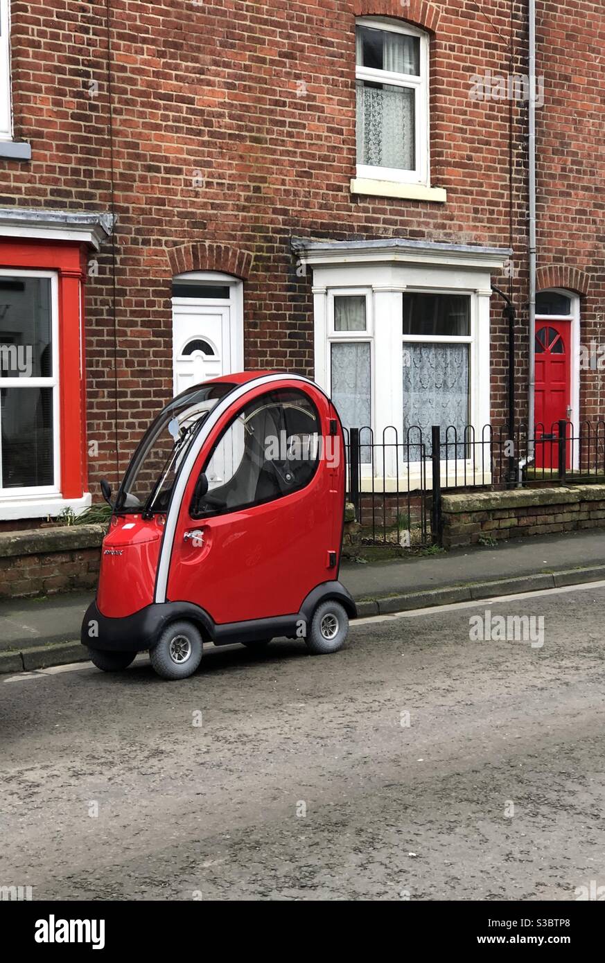 Red mobility Cabincar parked at the roadside Stock Photo - Alamy