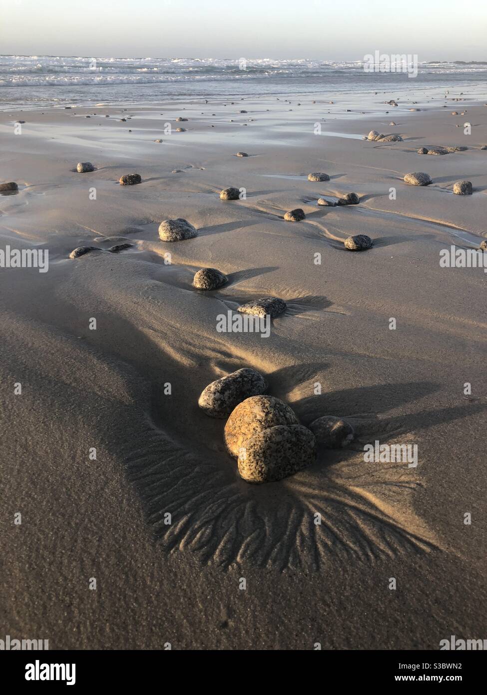 Receding tide creates patterns in the sand around pebbles in asilomar ...