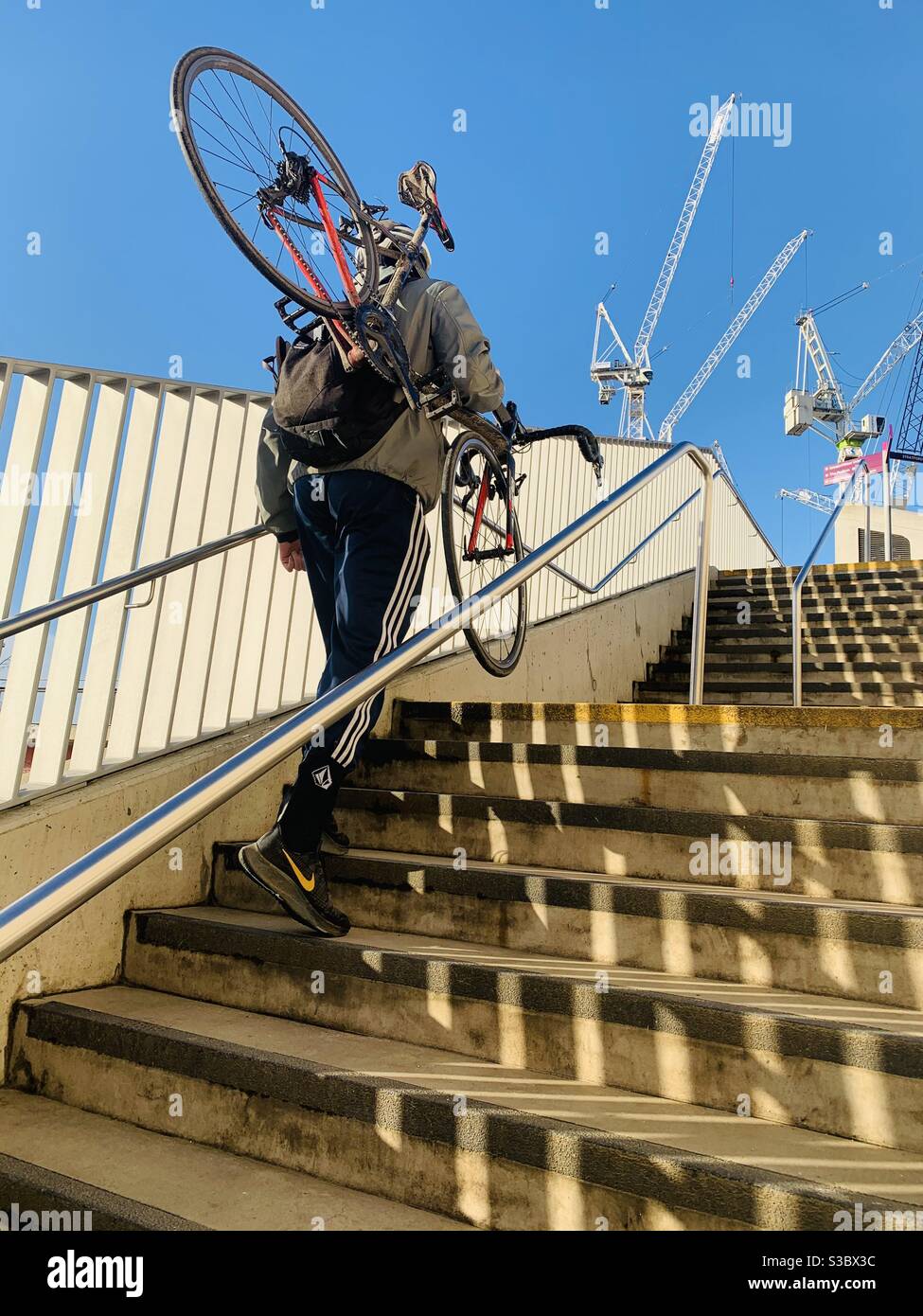 Man carrying bike up steps at Olympic park Stratford Stock Photo - Alamy