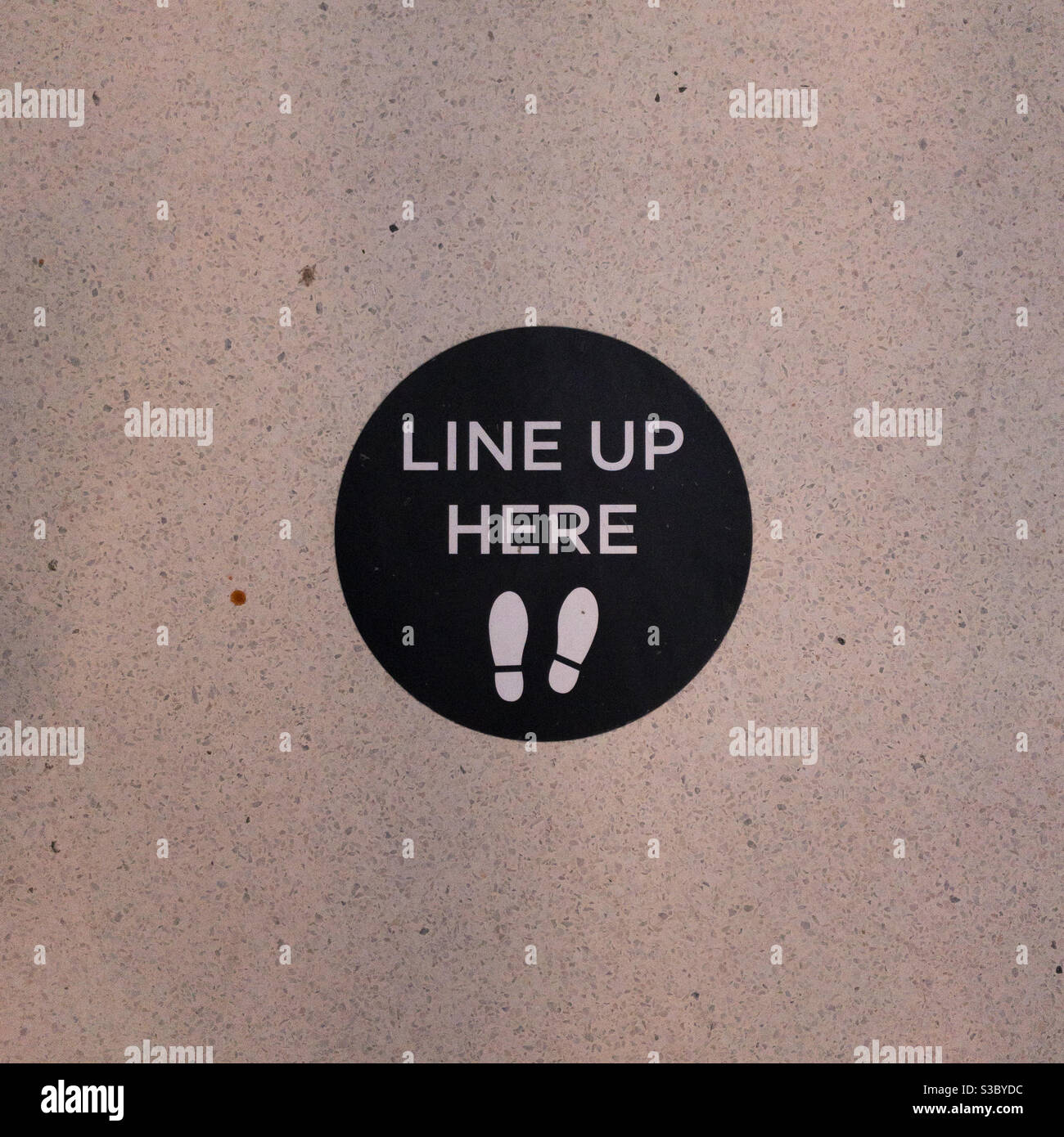 Line up here sticker on floor in shopping mall Stock Photo - Alamy
