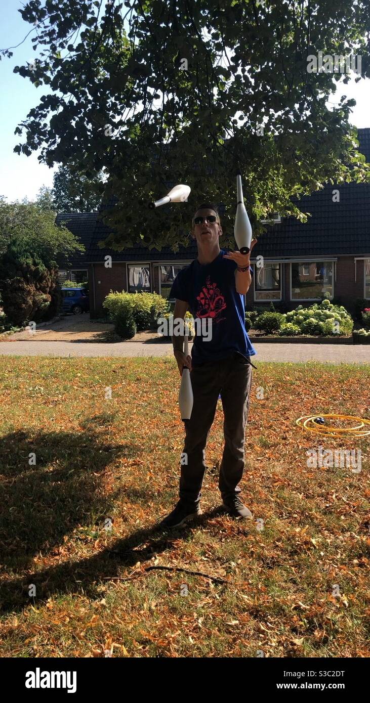 Circus performer juggling clubs under a tree in shadow Stock Photo - Alamy