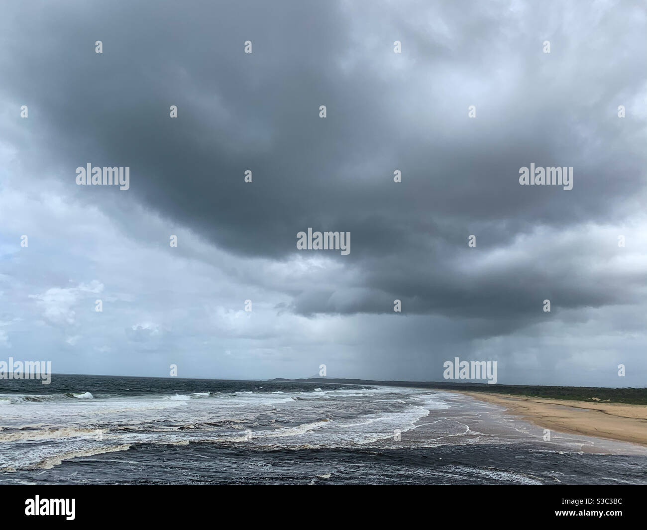 Stormy waters, a line of dark clouds filling the shoreline leading to ...