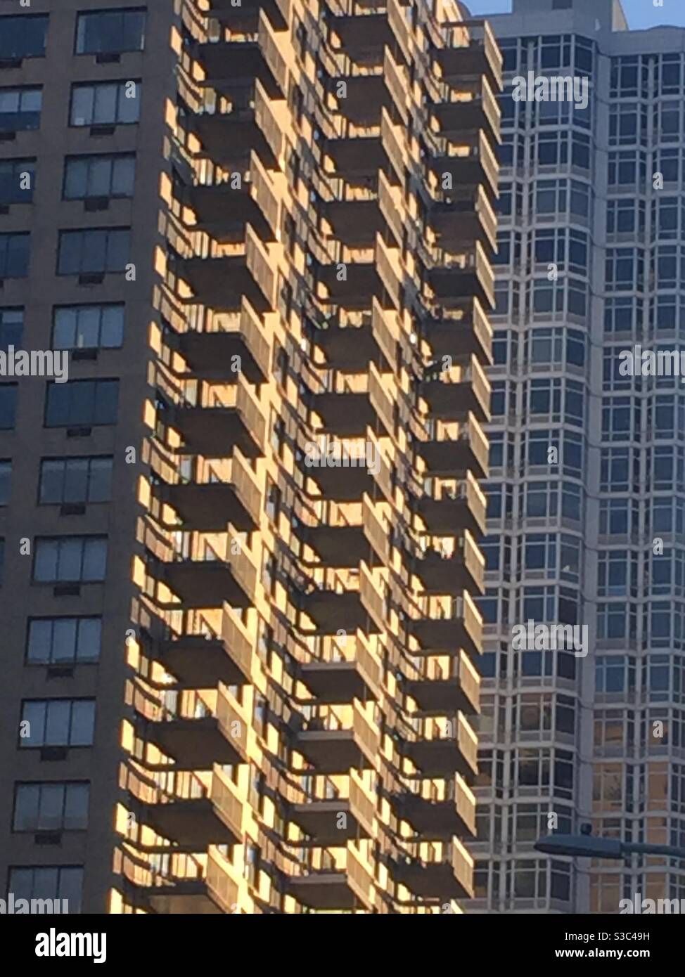 The late afternoon sun lights up balconies on an apartment building in ...