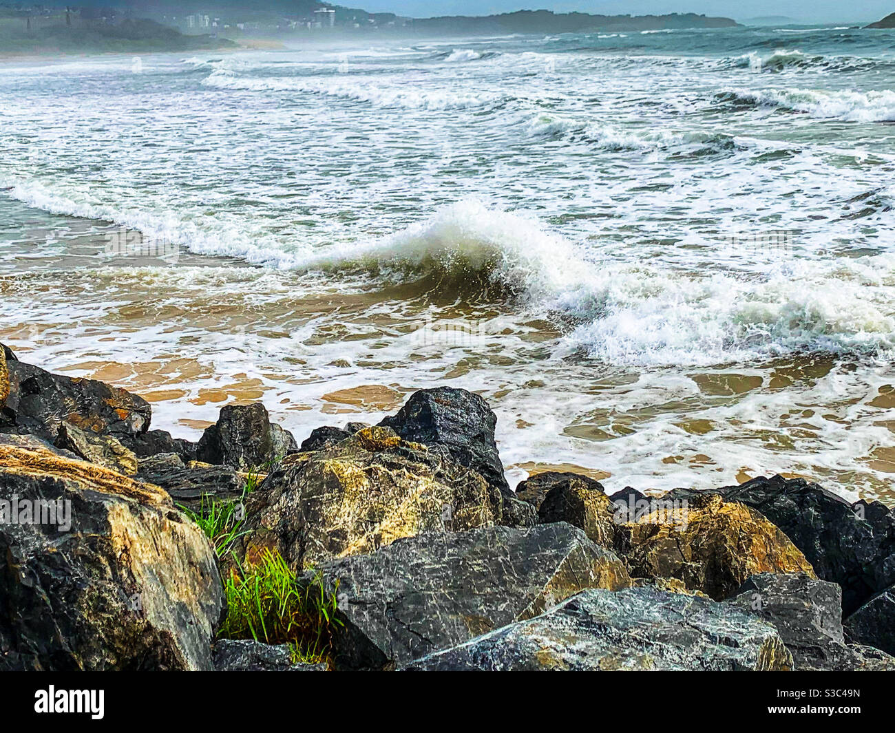 Foamy salt water, little lip shaped wave at the edge of the beach ...