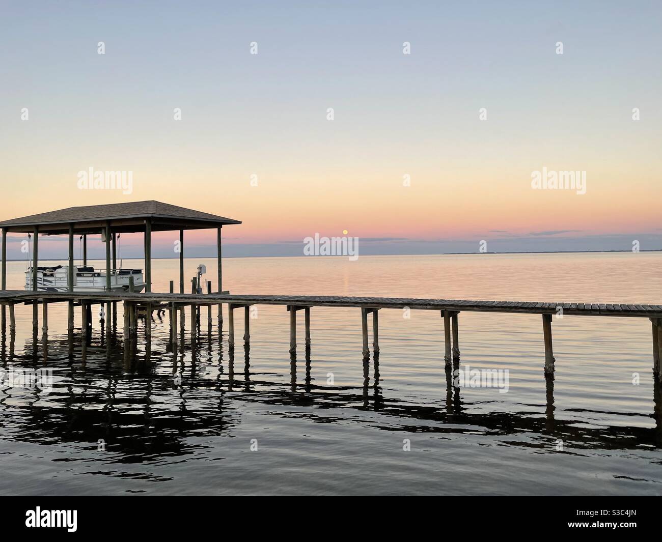 Last full moon of 2020 setting over bay water with a pontoon boat and ...