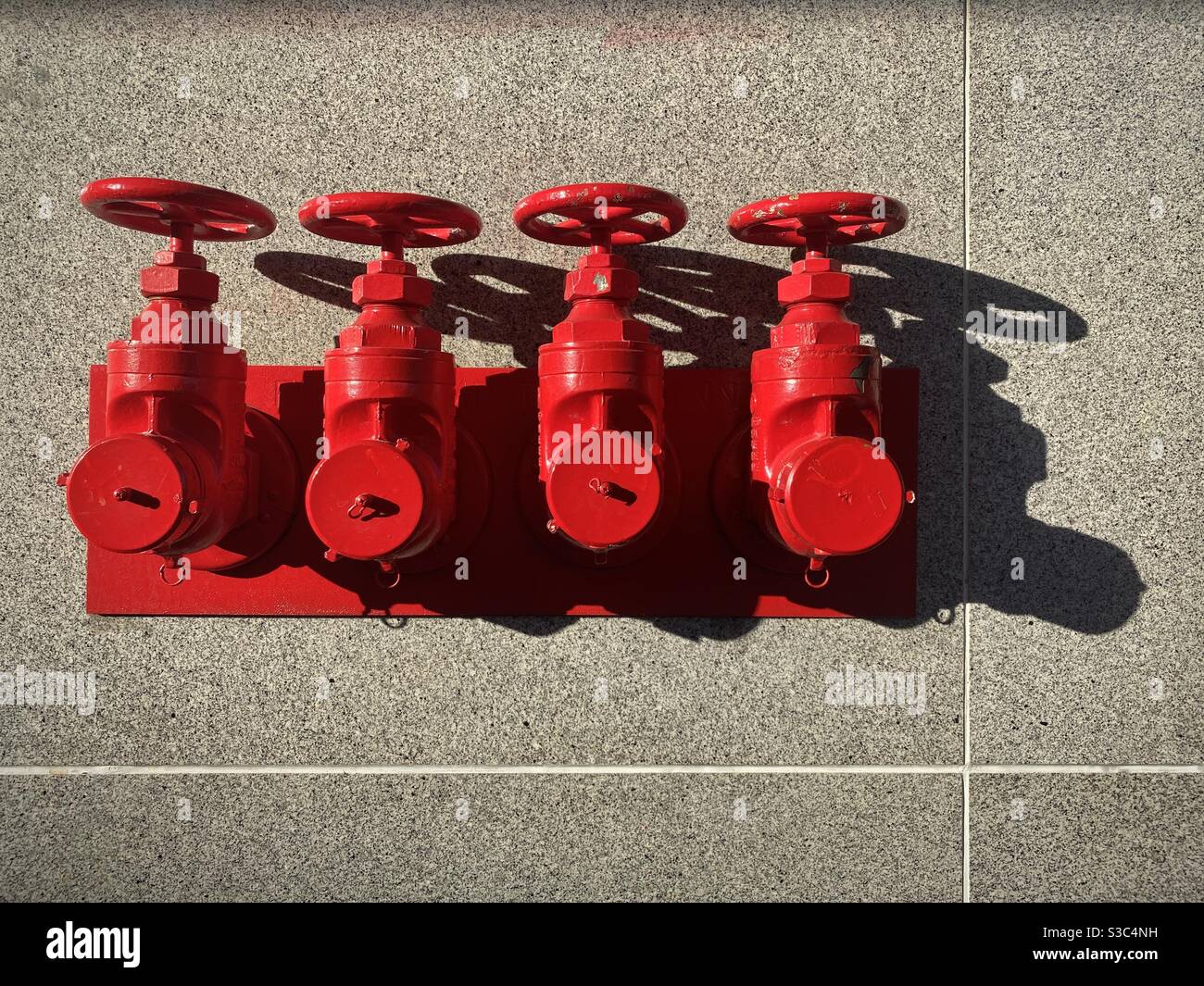 Bright red fire extinguisher connectors and taps on the outside of a ...