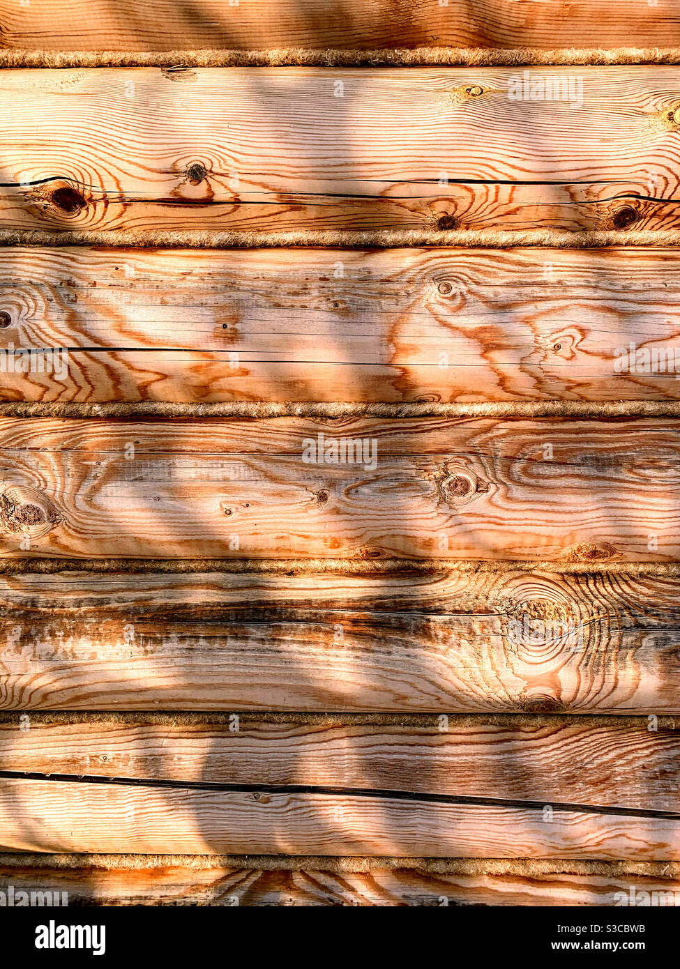 Wall of logs with sun and shadows Stock Photo - Alamy