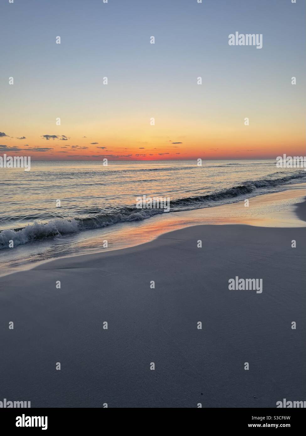 Sunset with color reflections onto sand over the Gulf of Mexico Destin ...