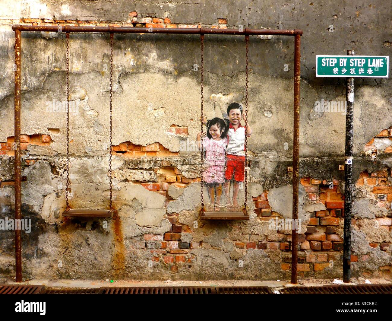 Brother and sister on a swing street art by Louis Gan Georgetown Penang Malaysia Stock Photo - Alamy