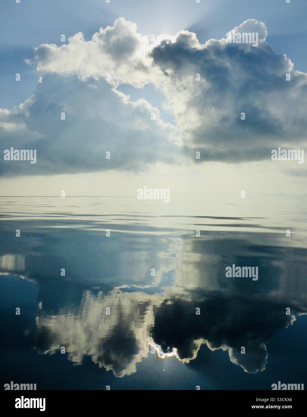 Clouds reflecting in completely still sea Stock Photo - Alamy
