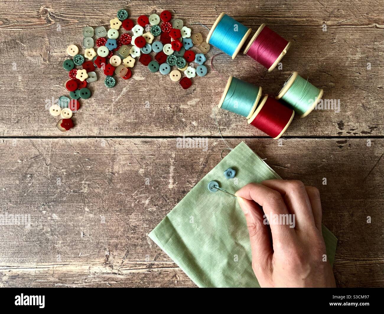 Sewing buttons onto fabric Stock Photo - Alamy