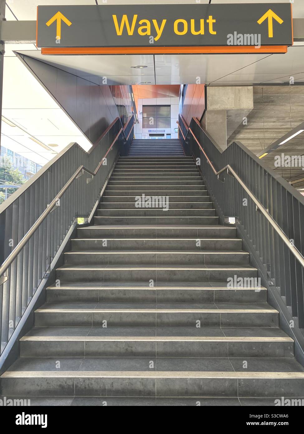 Orange ‘way out’ sign at top of stairs Stock Photo - Alamy