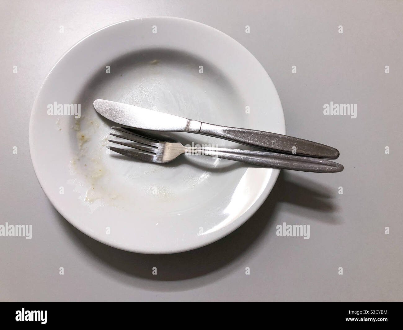 Empty plate with cutlery after a meal Stock Photo - Alamy
