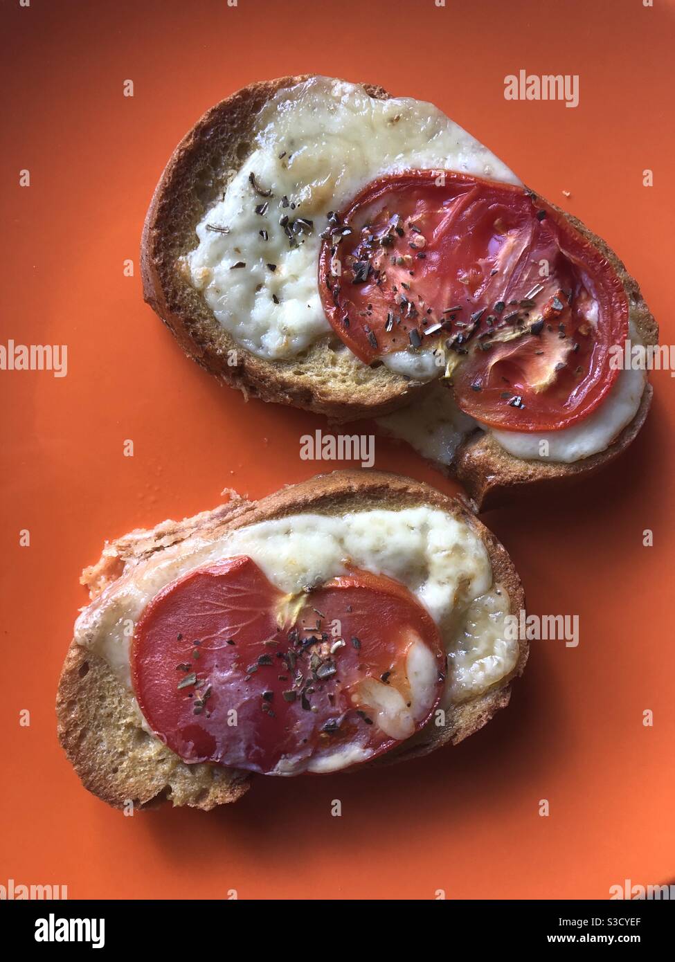 Mediterranean style breakfast toast with melted cheese and tomato on it ...