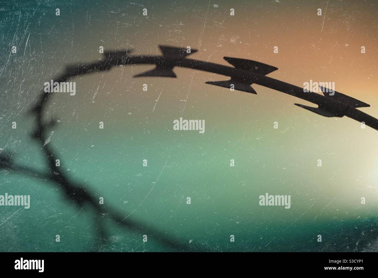 A close-up of razor wire or barbed wire with a colourful grungy ...