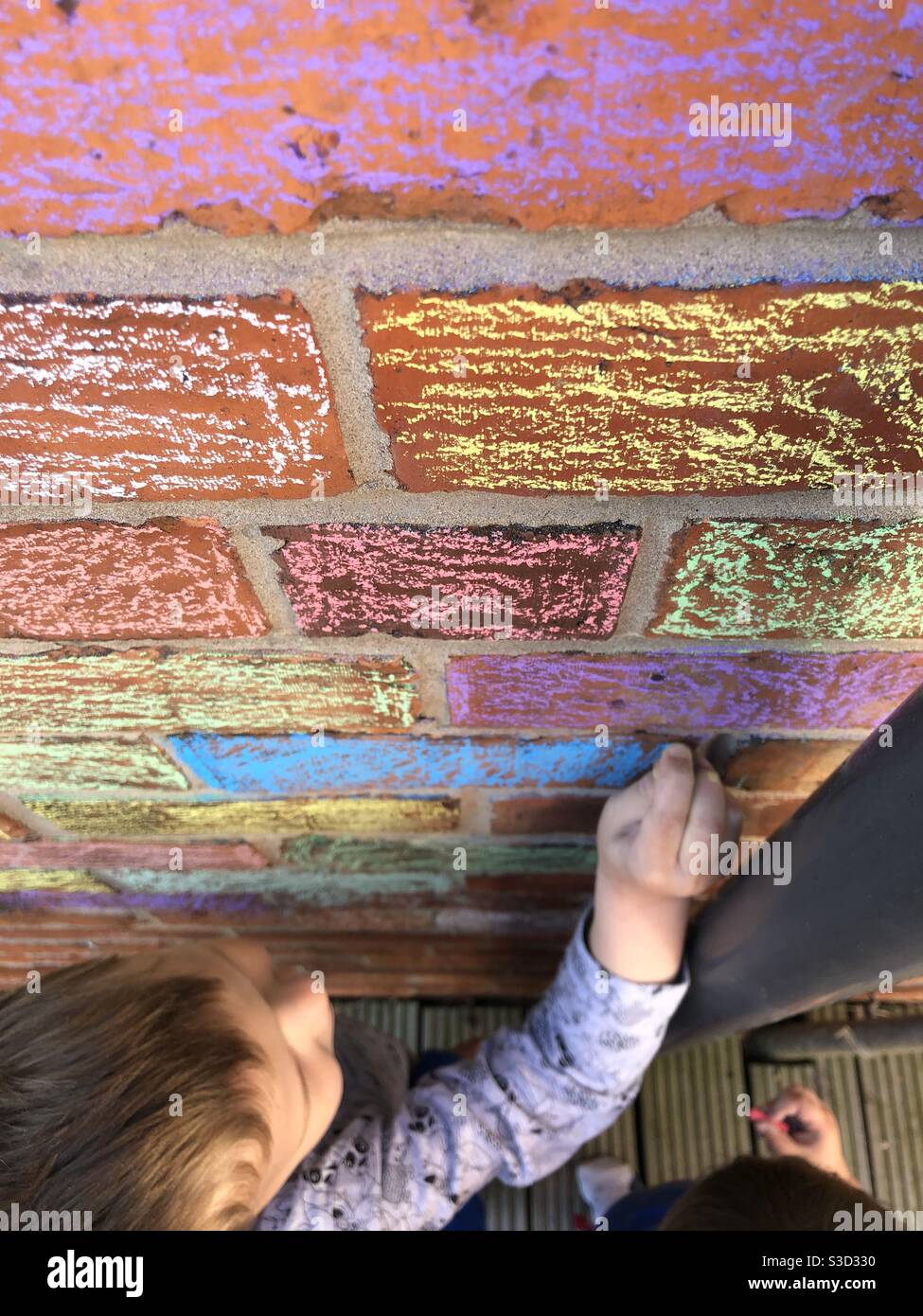 Children colouring brick wall with rainbow chalks Stock Photo - Alamy