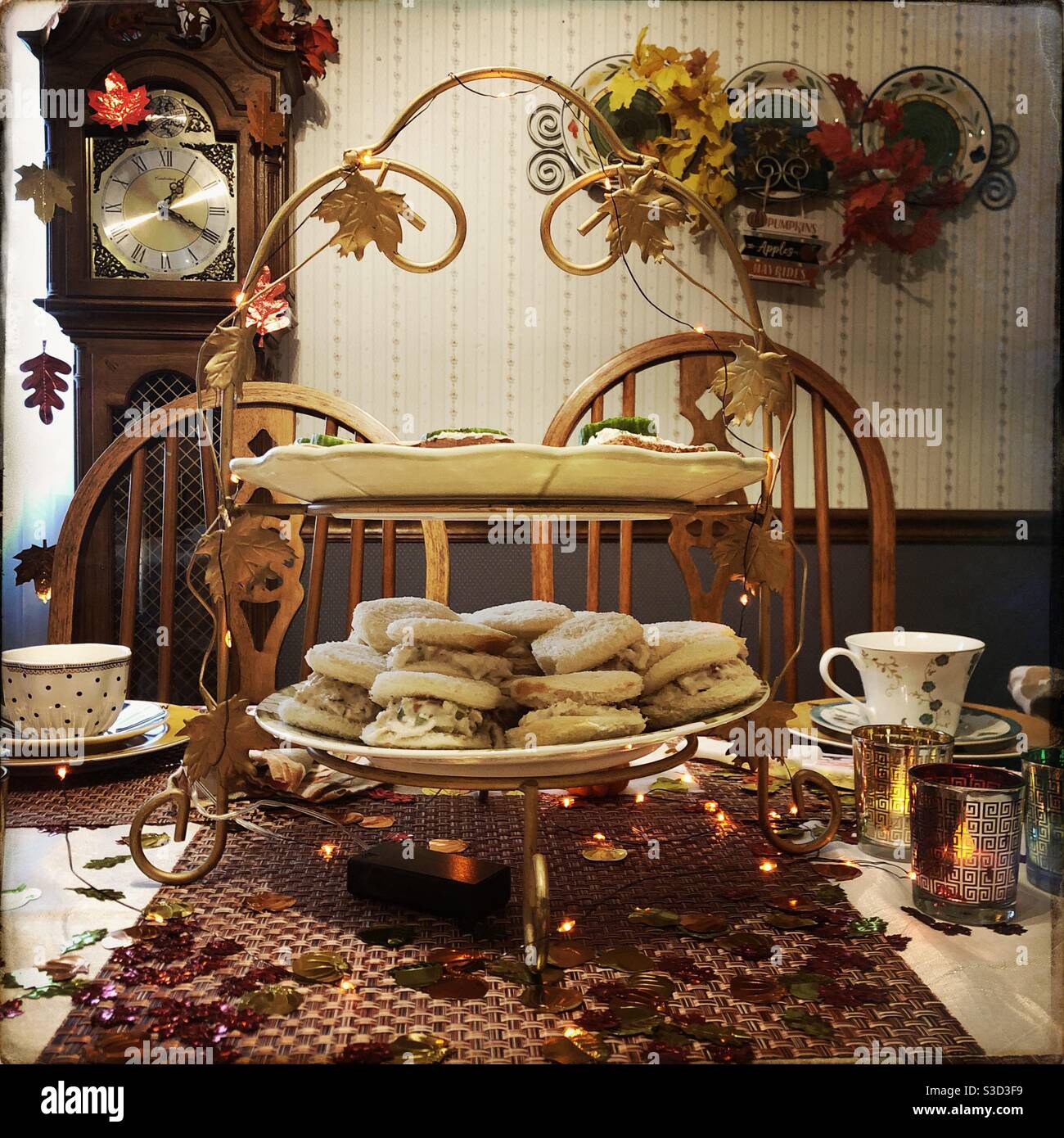 A fall tea party setting with a tier server full of finger sandwiches ...