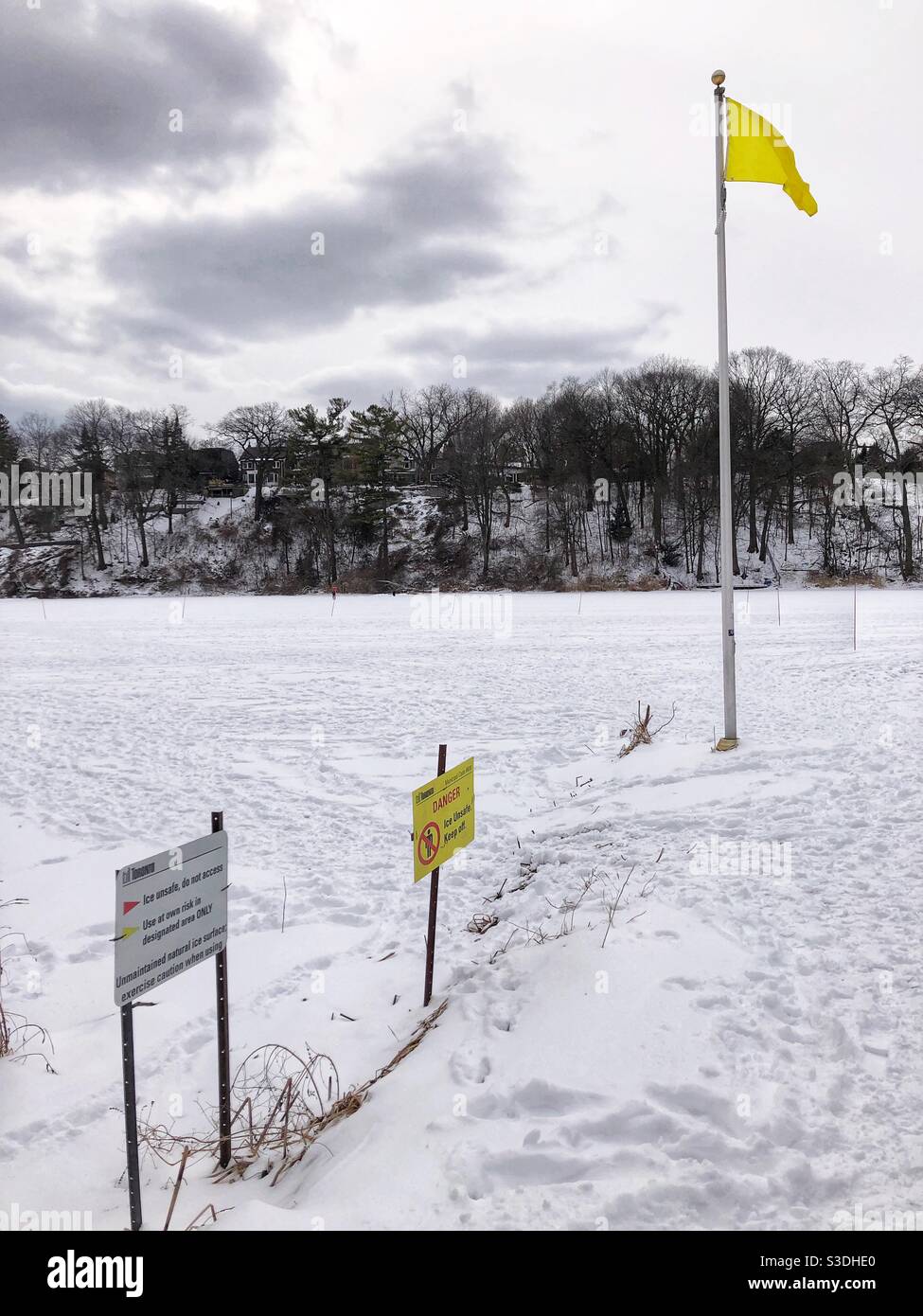 Yellow warning flag at the edge of a frozen pond Stock Photo - Alamy