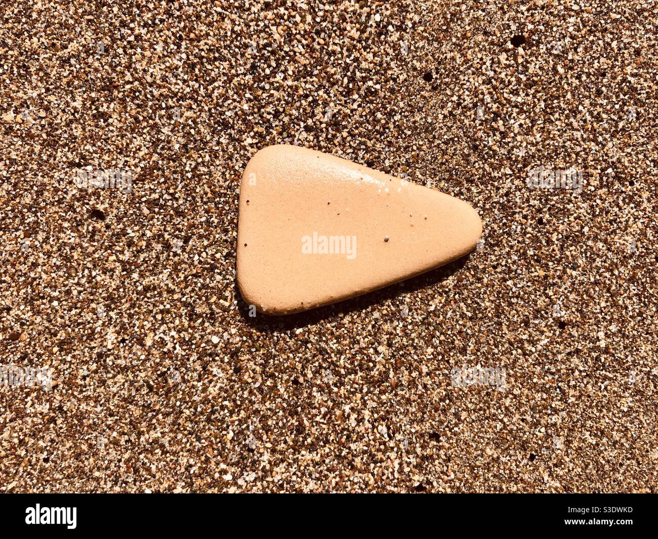 A rock that looks like a play button icon placed on sandy beach Stock ...