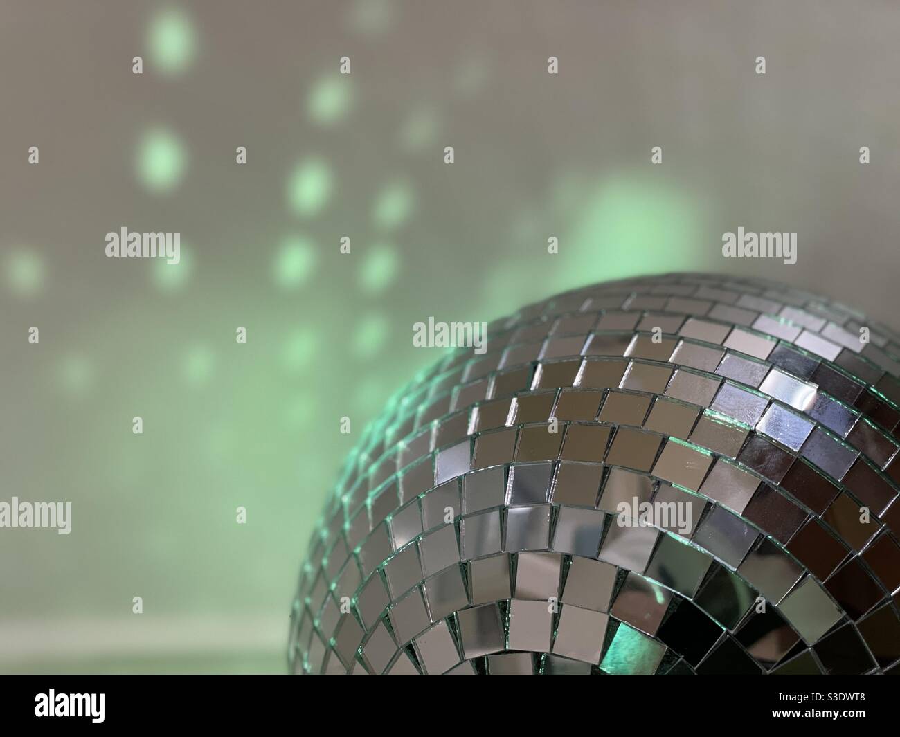 Disco ball with green lighting and patterns reflecting onto a wall ...